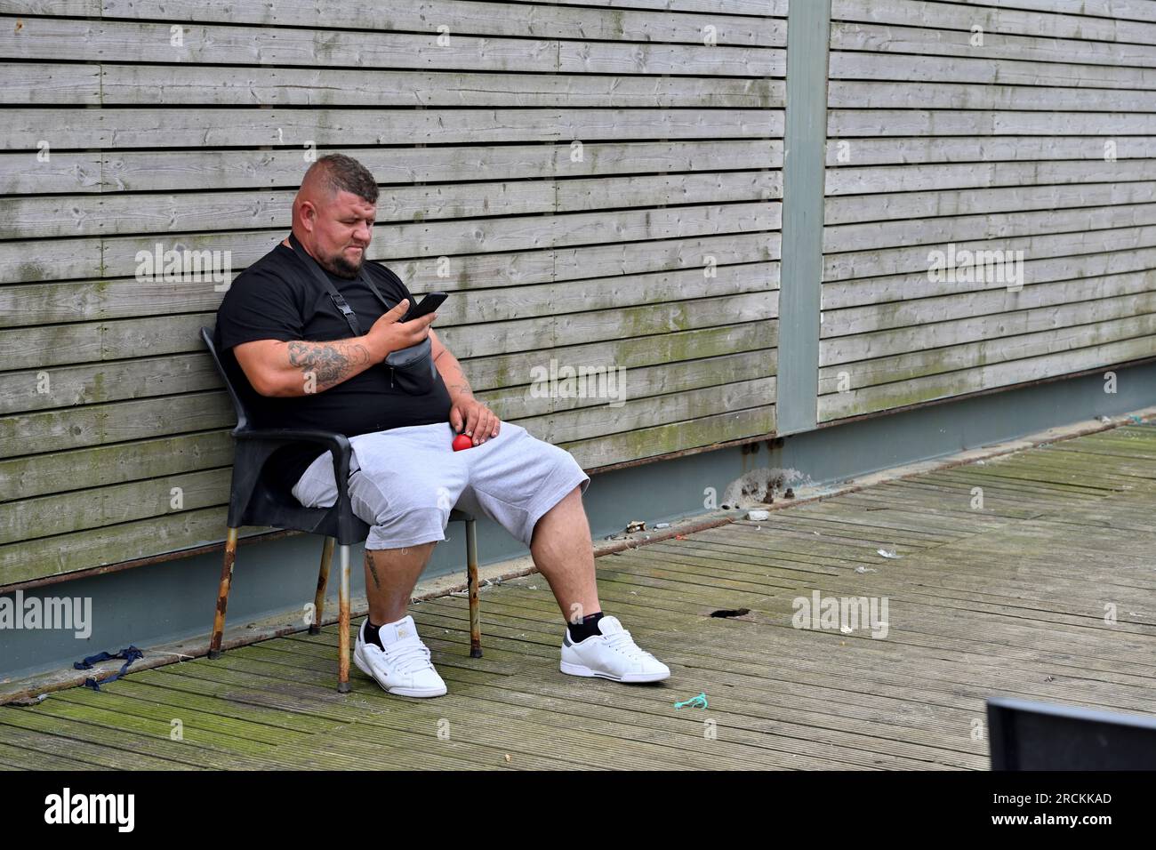 Heavy set Portuguese man (fisherman) sitting on old chair looking at ...