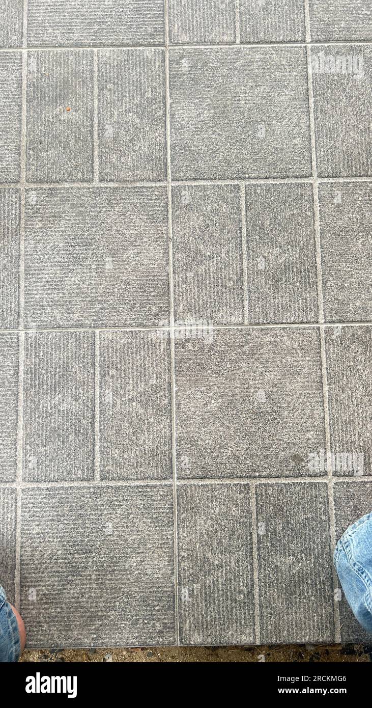 Detail of a woman's feet walking on a gray tile floor Stock Photo - Alamy