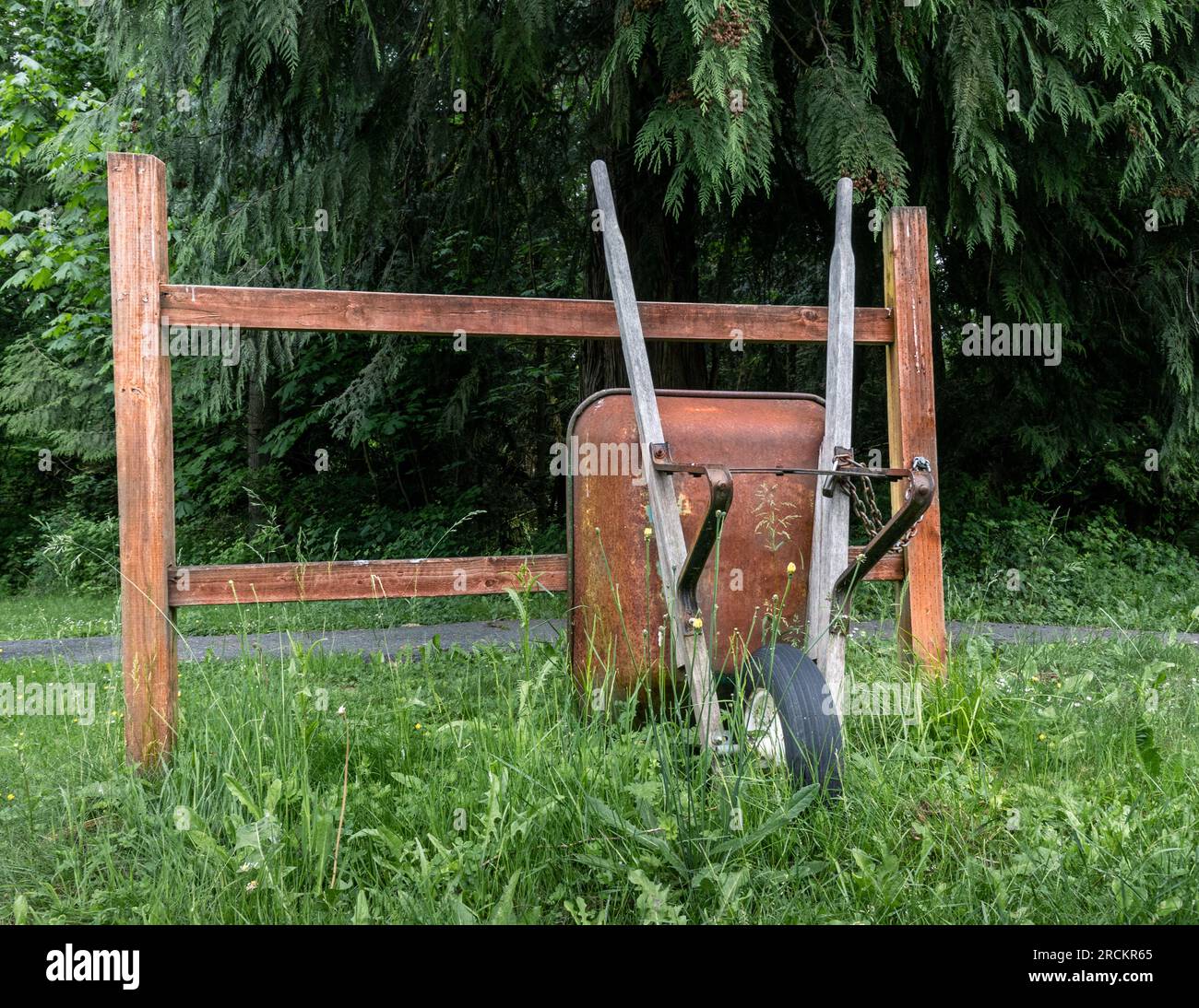 An old rusty wheel barrow leans against a picket fence Stock Photo - Alamy