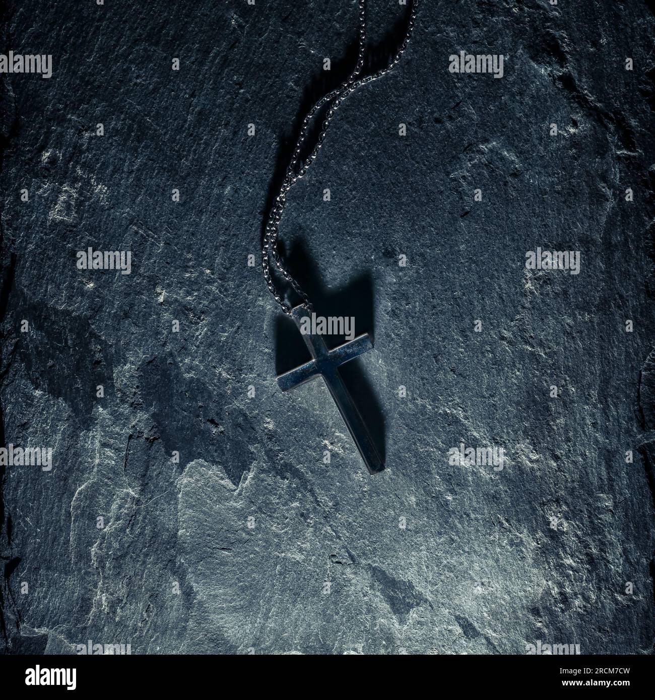 Christian cross necklace on slate background with the crucifix casting ...