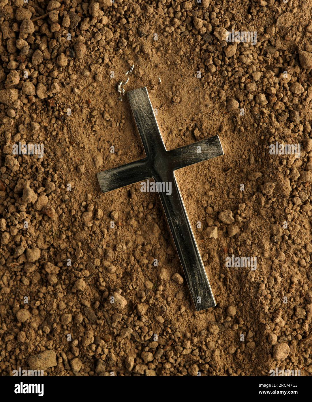 Christian cross necklace buried in ground with the dirt brushed away ...
