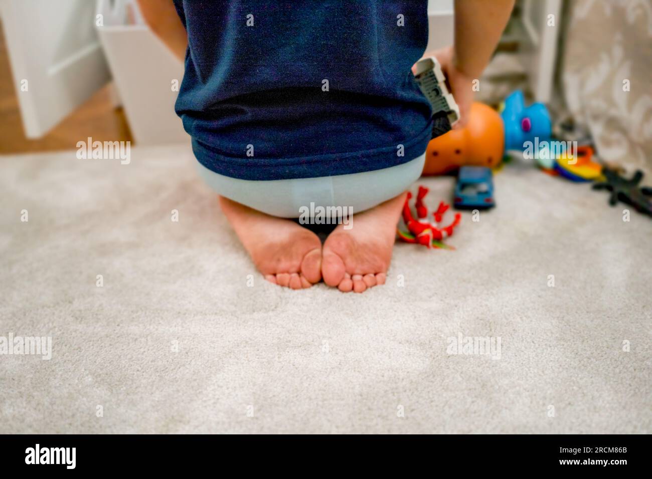 Close up little boy sitting on floor on back view playing at ...
