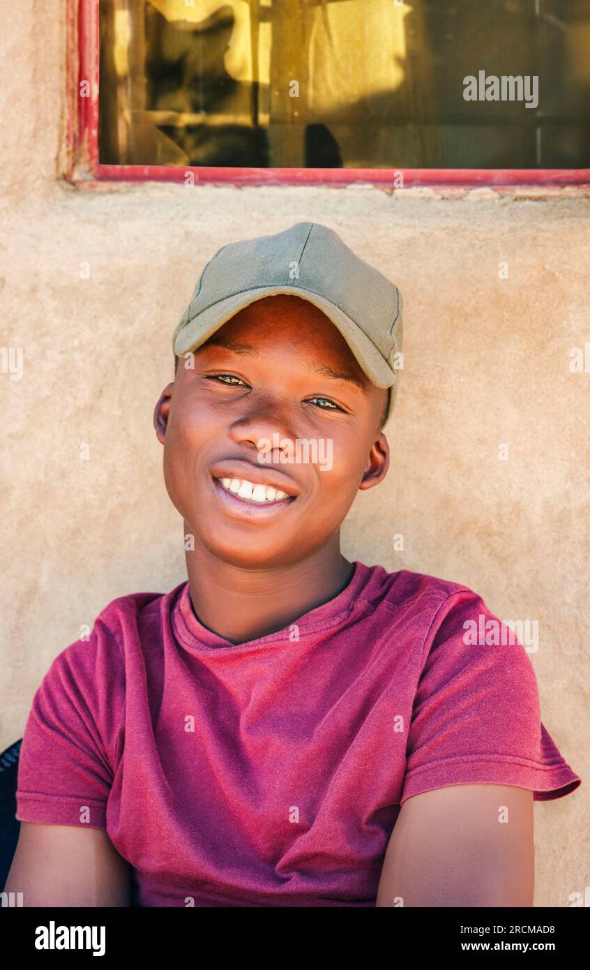 young african man in the village sitting down in front of his house ...