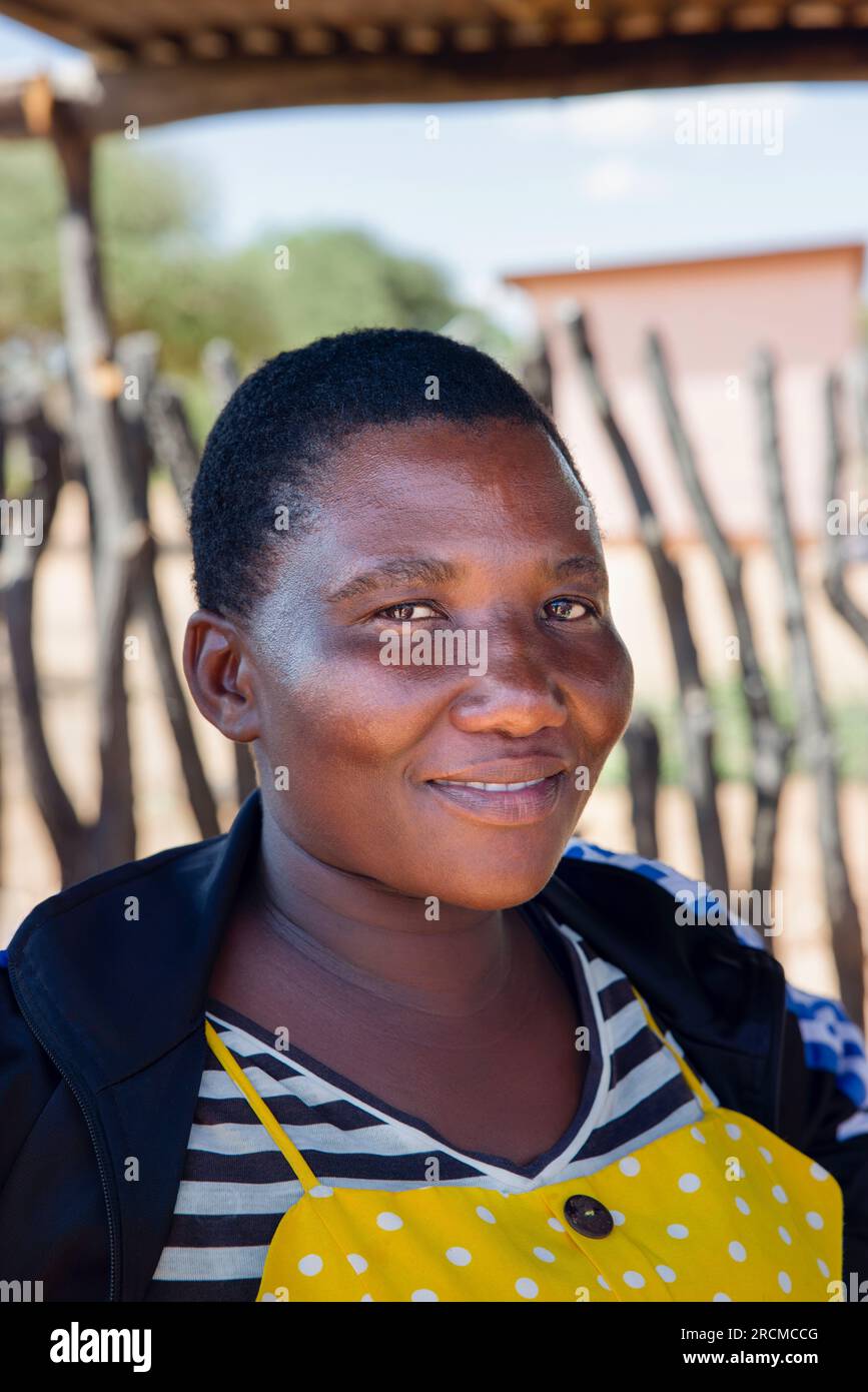 African village woman standing under the shade in the shack, outdoors ...