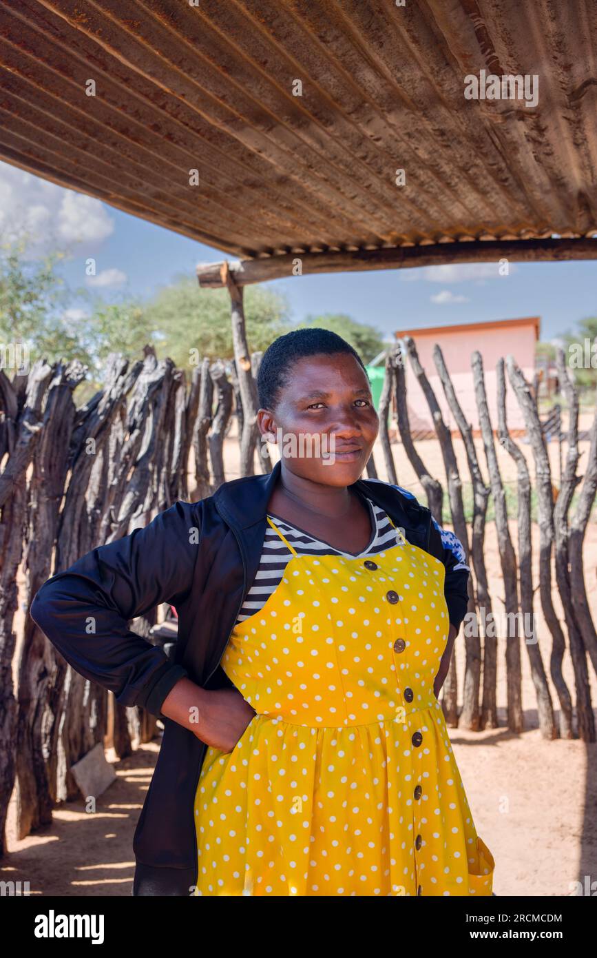 African village woman standing under the shade in the shack, outdoors ...
