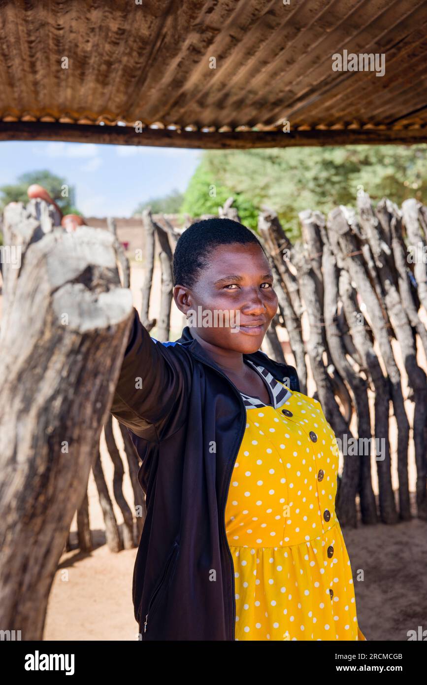 African village woman standing under the shade in the shack, outdoors ...