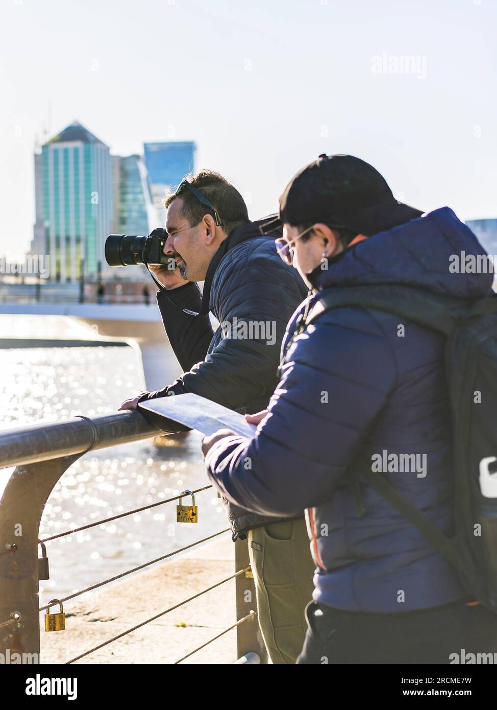 LGBT couple travelers. One is reading a map while the other is takings ...