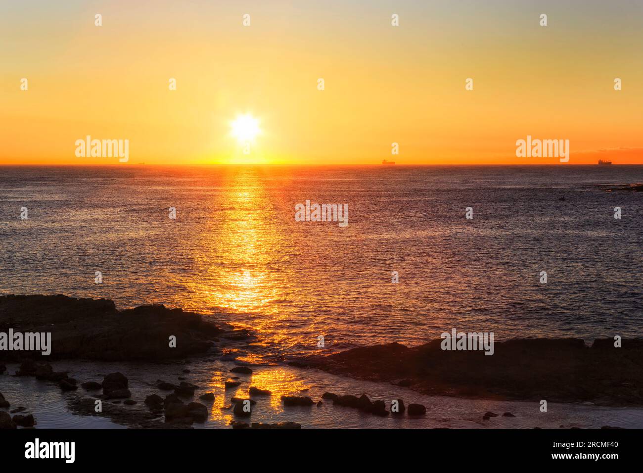 Scenic rising sun over Pacific ocean horizon of Swansea head cliffs in ...