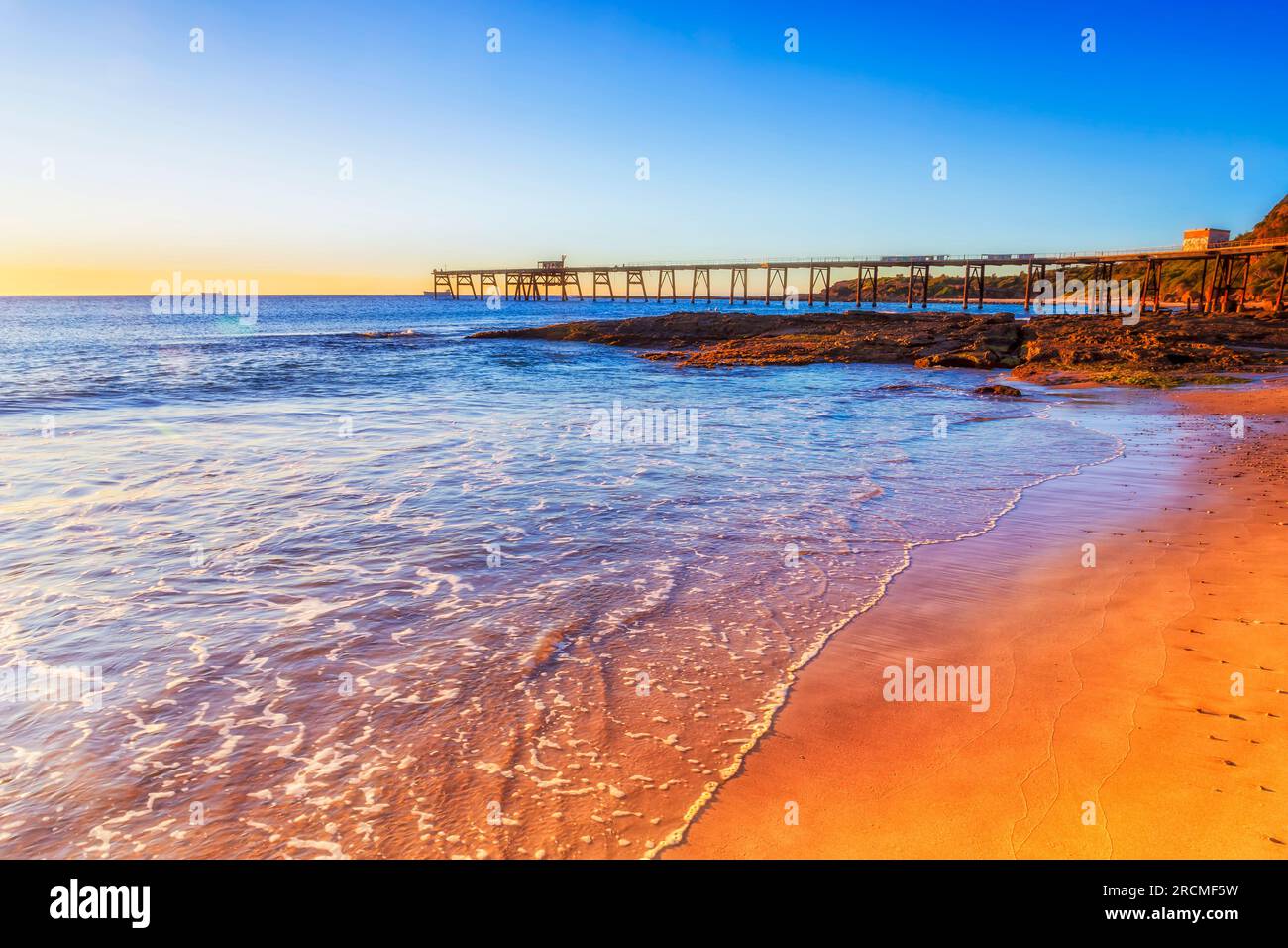 Sun lit sandy Middle camp beach at Catherine hill bay town on Pacific ...