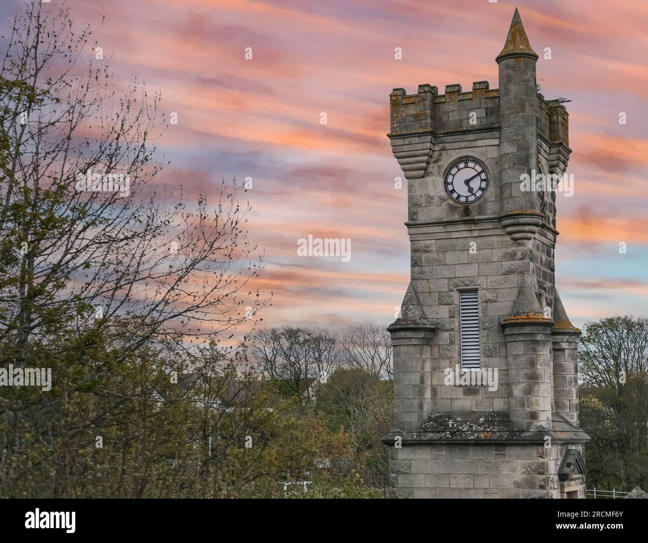 Tall old tower in a Scottish village against a beutiful pink and orange ...