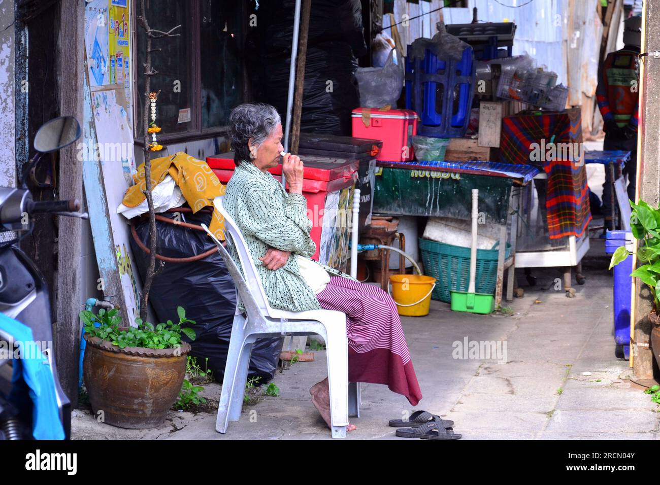 older, elderly woman, sits opposite new Thailand parliament, Sappaya ...
