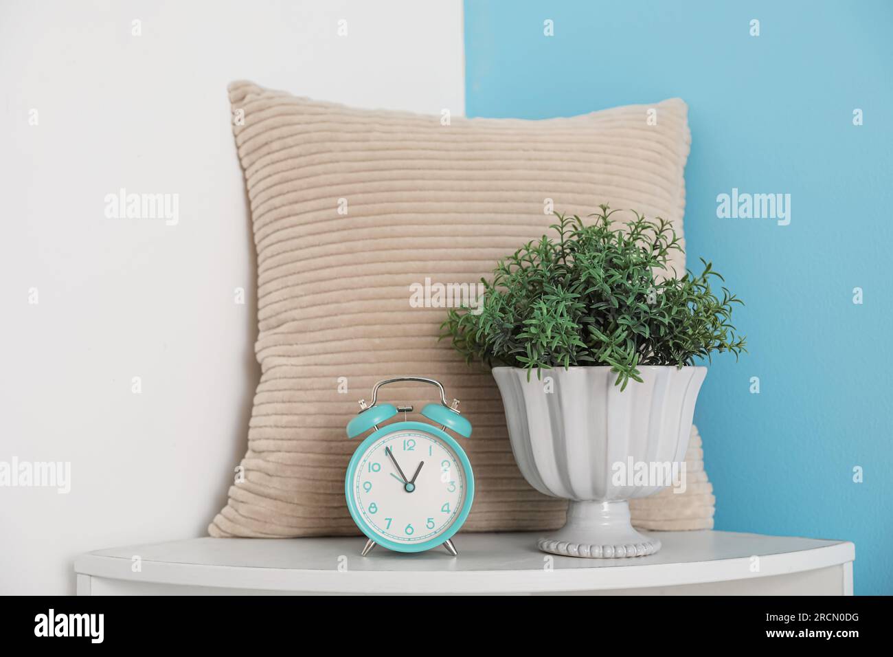 Vintage alarm clock with houseplant and pillow on shelf in room Stock ...