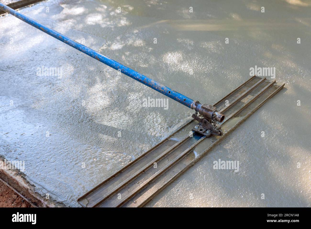 Concrete for driveway is being leveled by workers on construction site ...