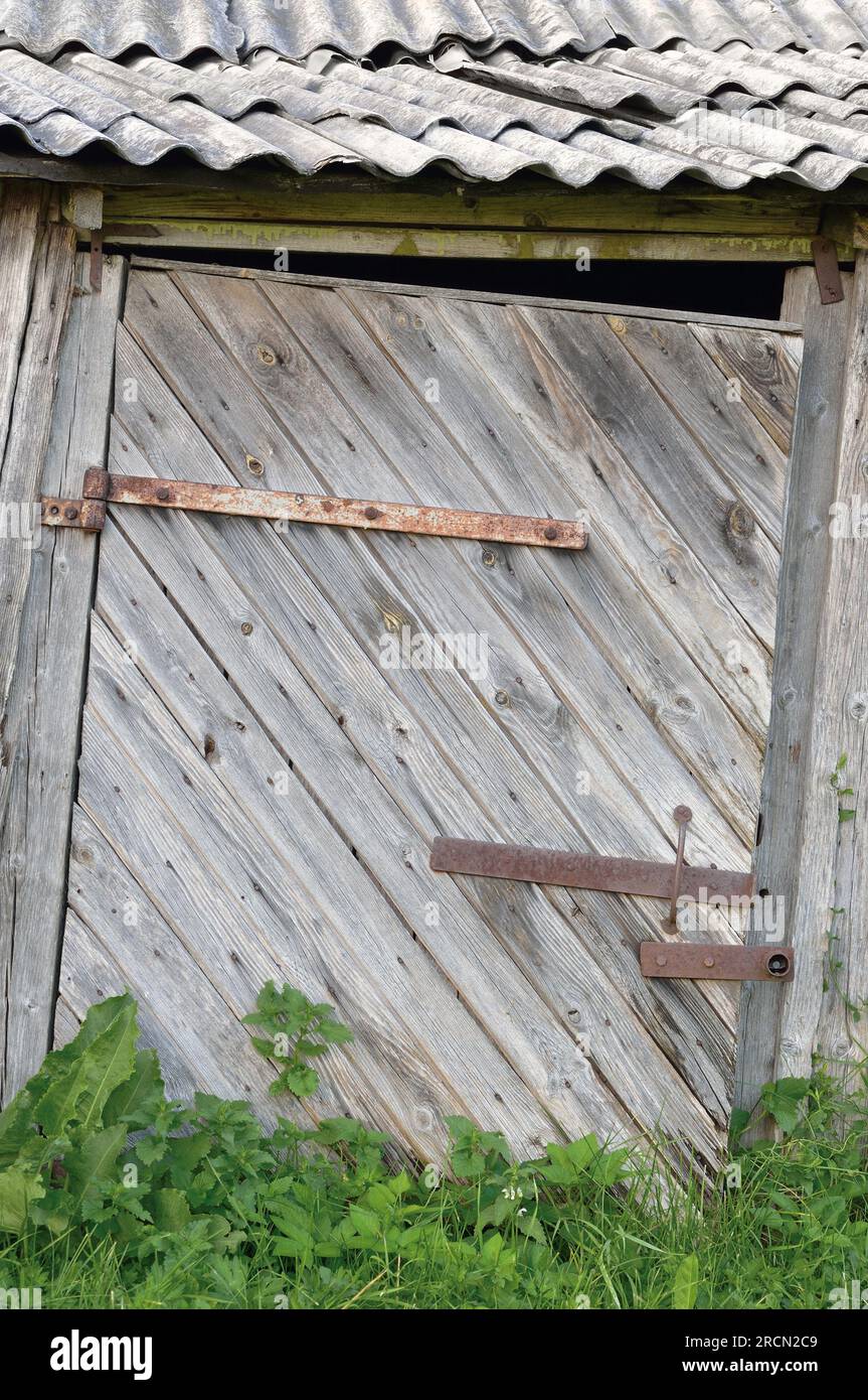 Old aged weathered wooden barn shack door, grey wood boarding hut wall planks, rusted metal ...