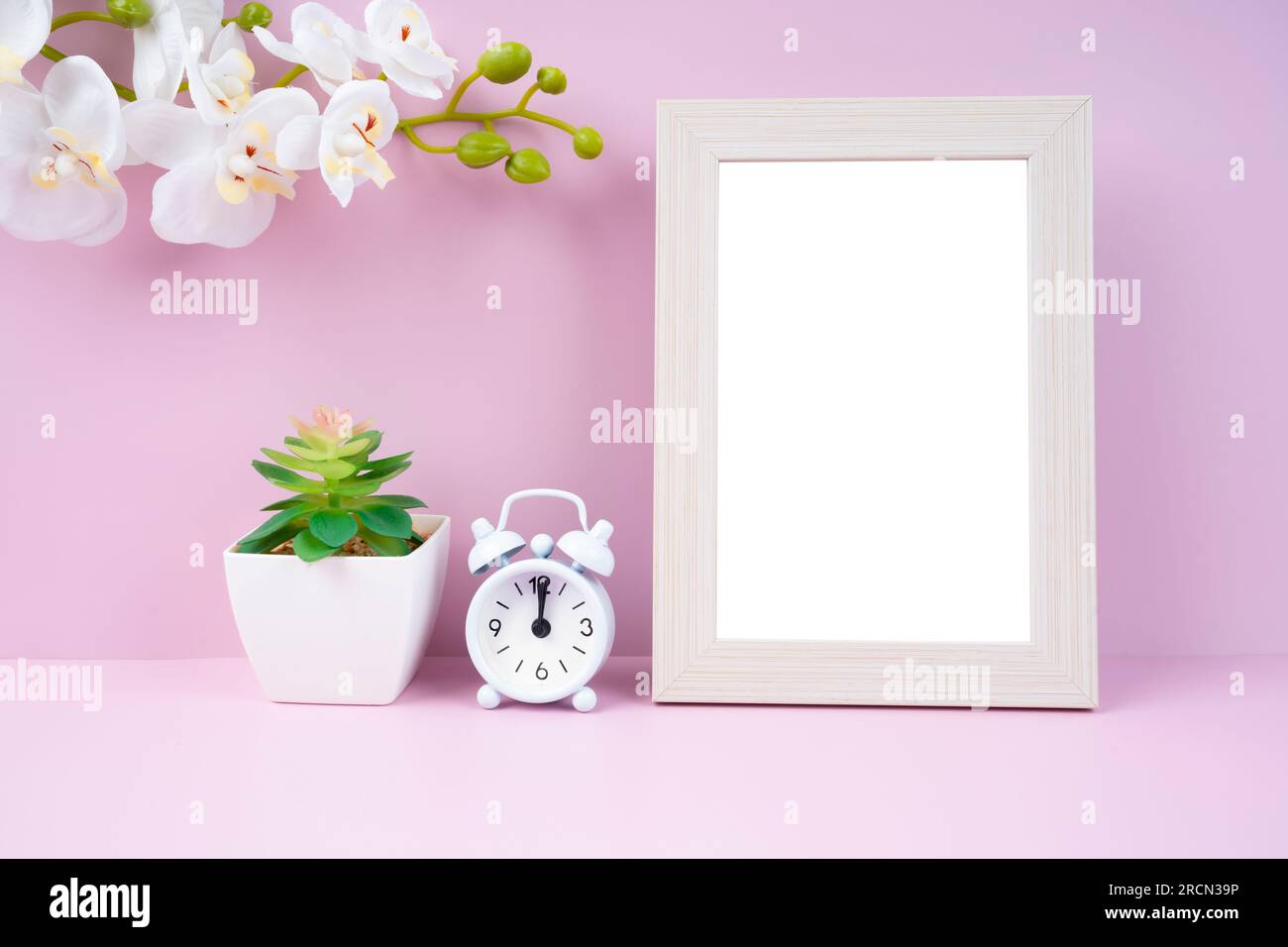 Blank picture frame and alarm clock on pink color background with copy ...