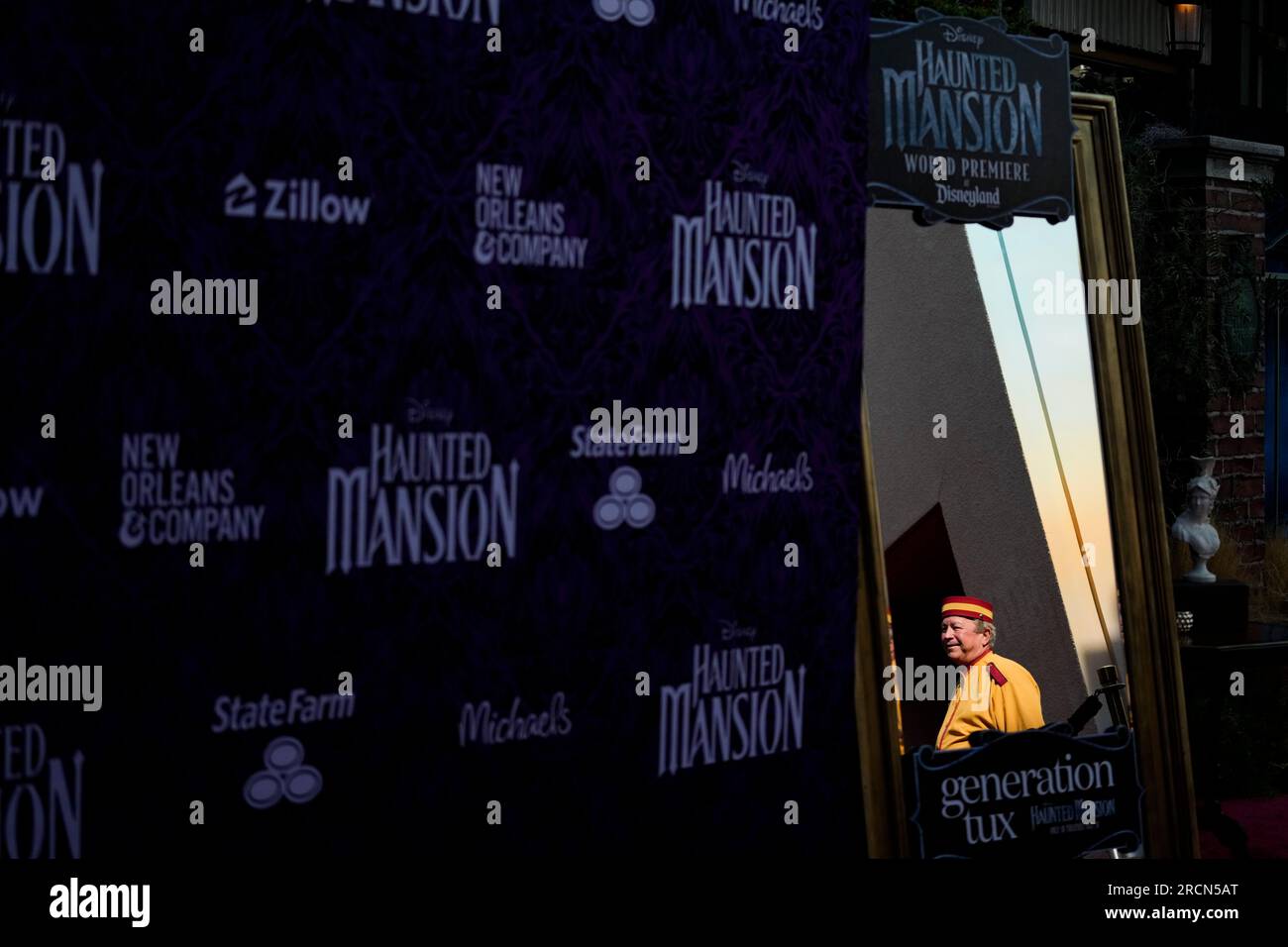 A man dressed as a bellman stands near an empty red carpet at the world ...