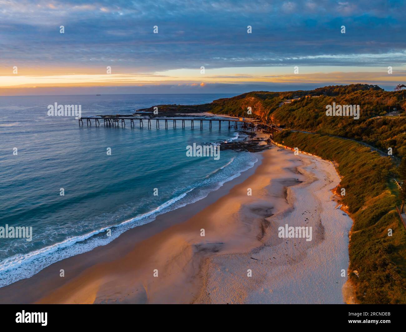 Sunrise seascape with cloud filled sky and the old coal loading jetty ...