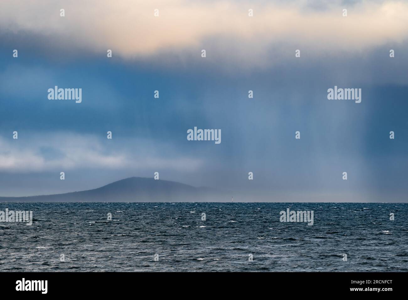Distant view of heavy rain falling over a distant coastline at ...