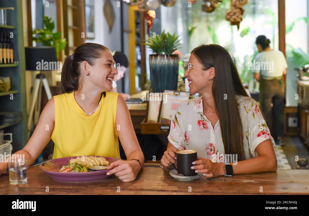 Two best friends talking and eating in a cafe Stock Photo - Alamy