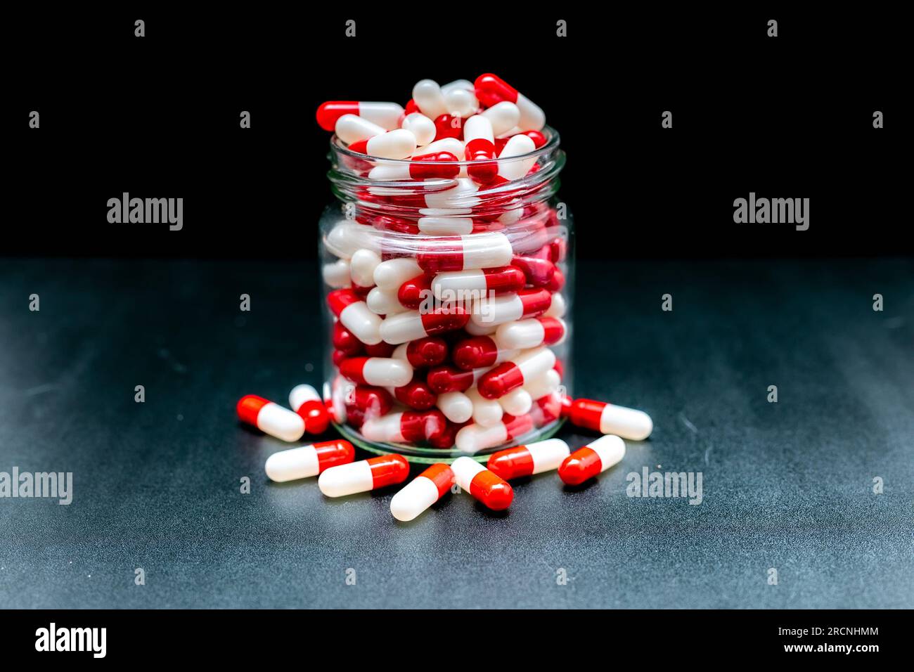 White-red capsule many pieces in one jar with black background Stock ...