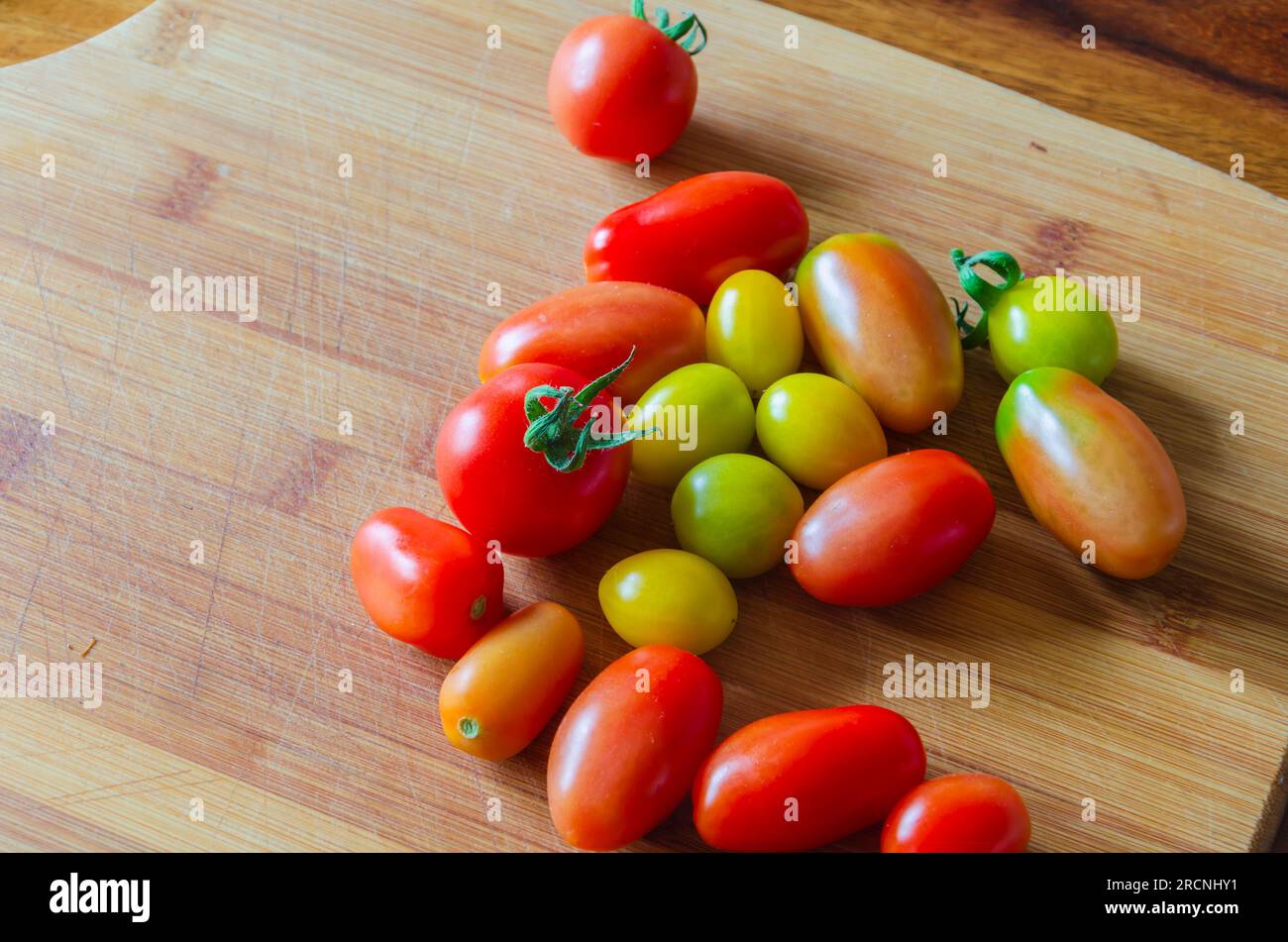 Multi coloured tomatoes sitting on a natural wood chopping board Stock ...