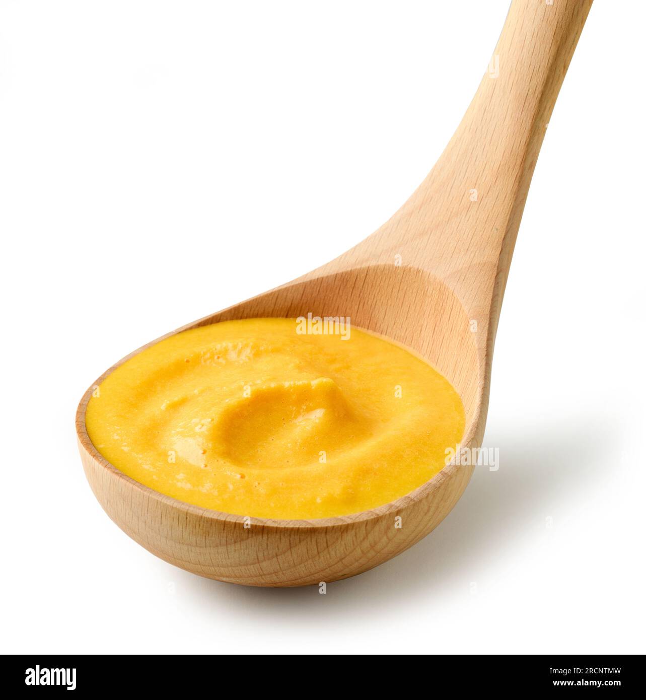 yellow vegetable puree in wooden ladle isolated on white background ...