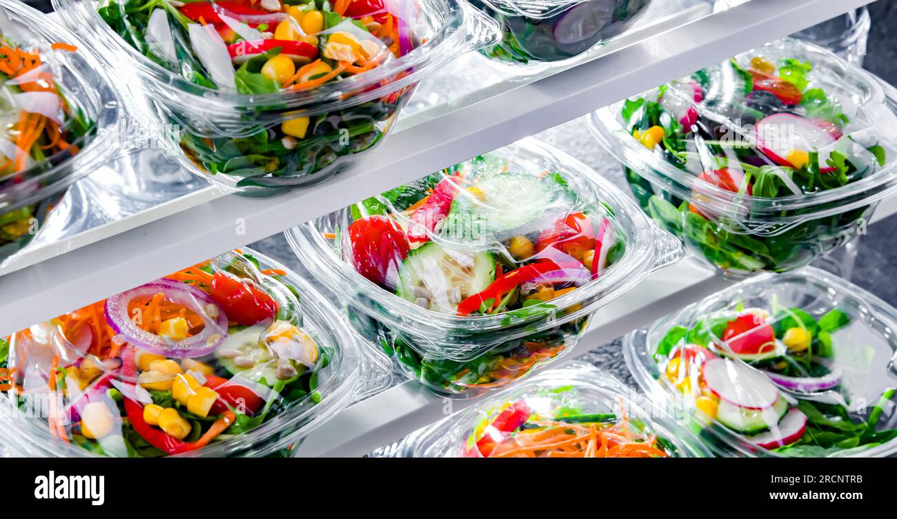 Plastic boxes with pre-packaged vegetable salads, put up for sale in a ...