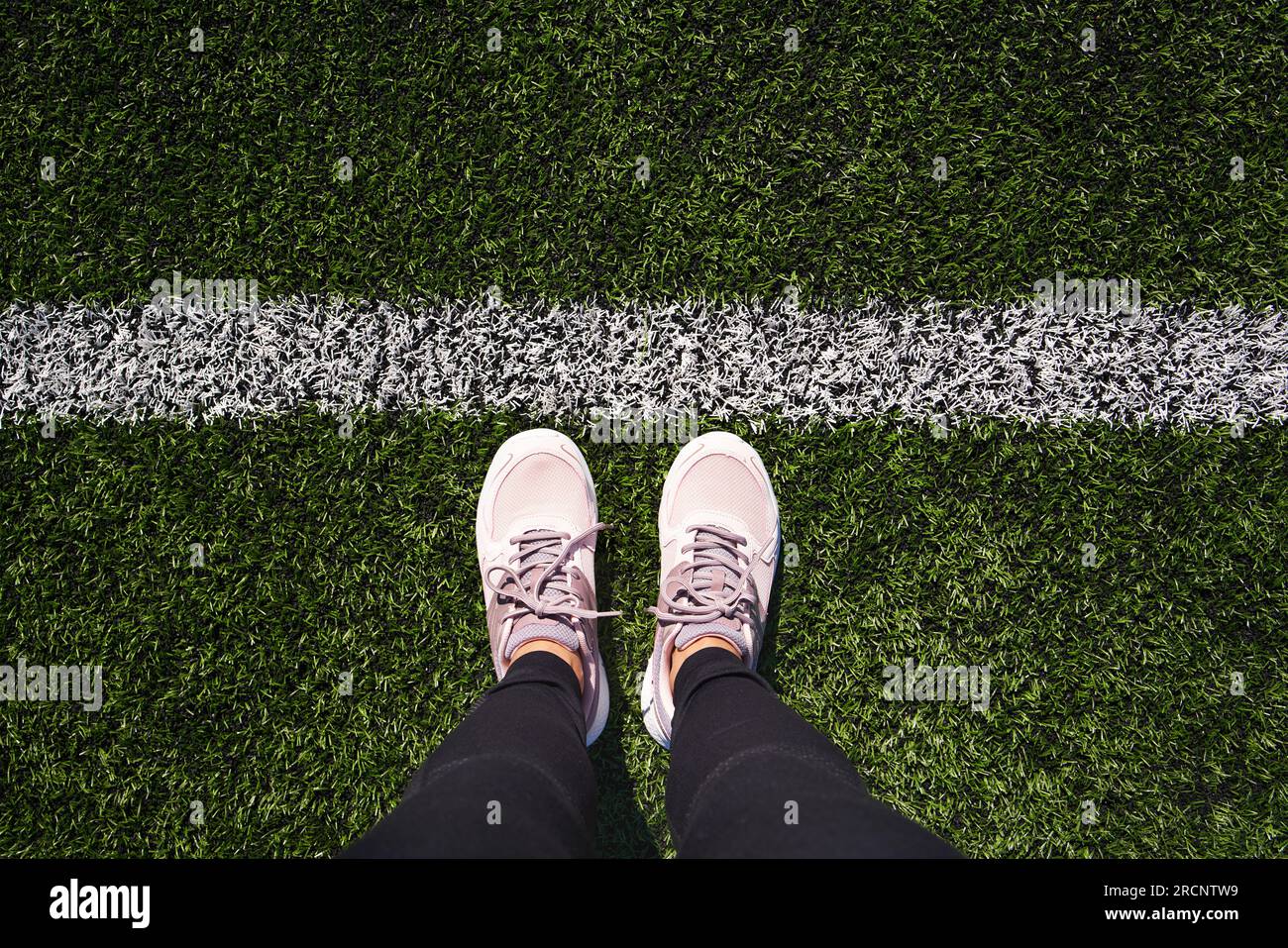 Legs of a woman standing on a sports playground behind a white starting ...