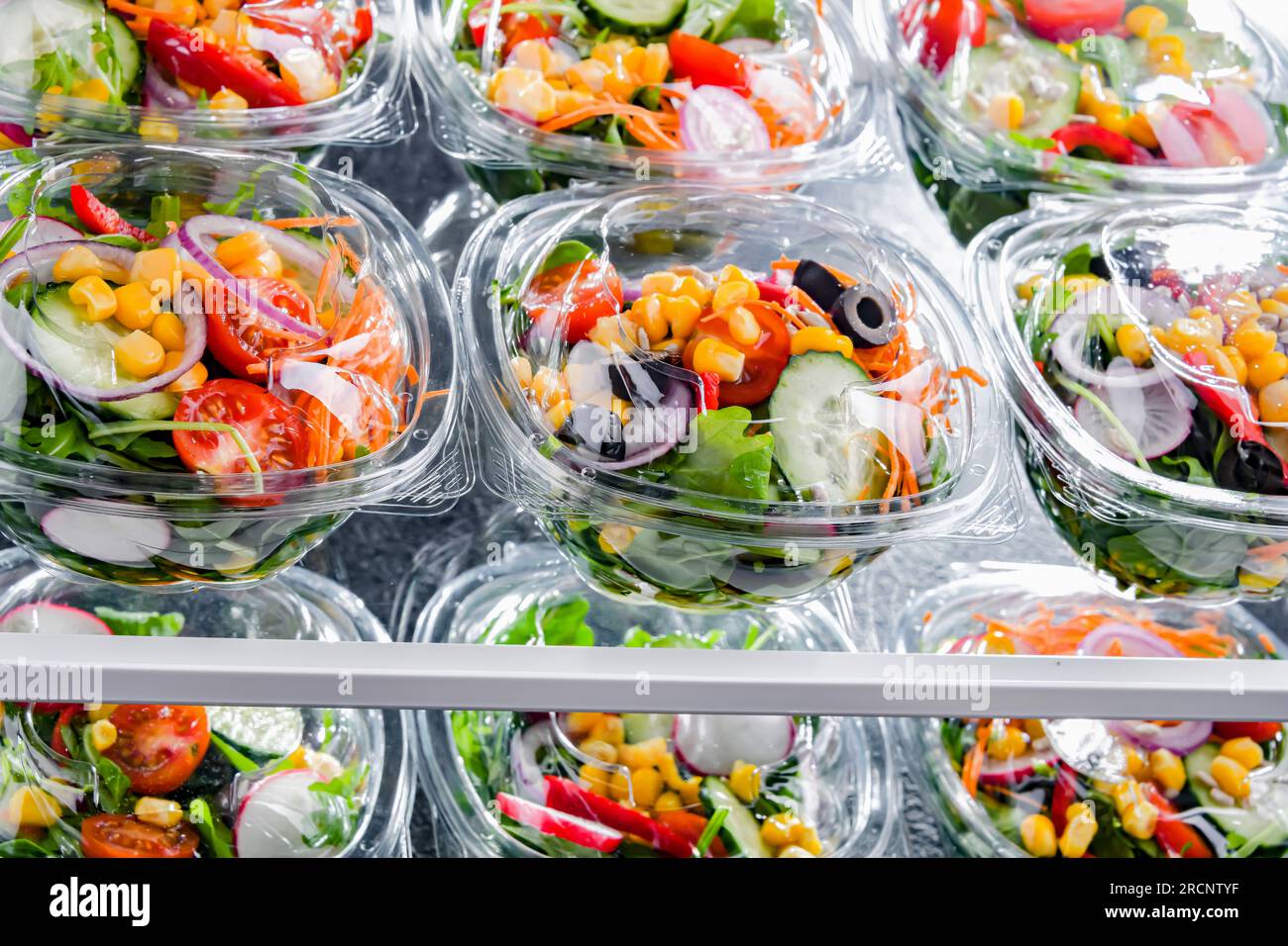 Plastic boxes with pre-packaged vegetable salads, put up for sale in a ...