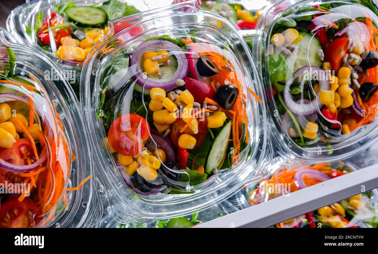 Plastic boxes with pre-packaged vegetable salads, put up for sale in a ...