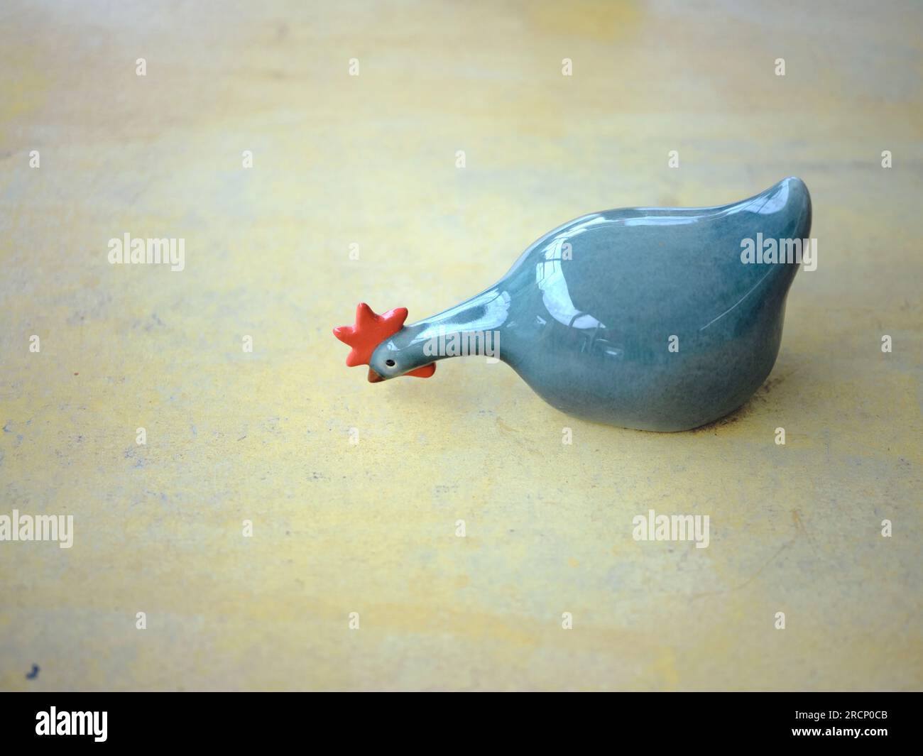 Ceramic figurine of a chicken on wood backgrounds. Handmade clay blue ...