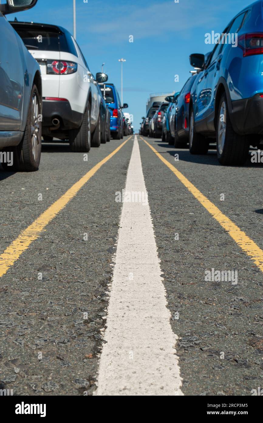 Two queues of cars waiting on either side of white and yellow lines ...