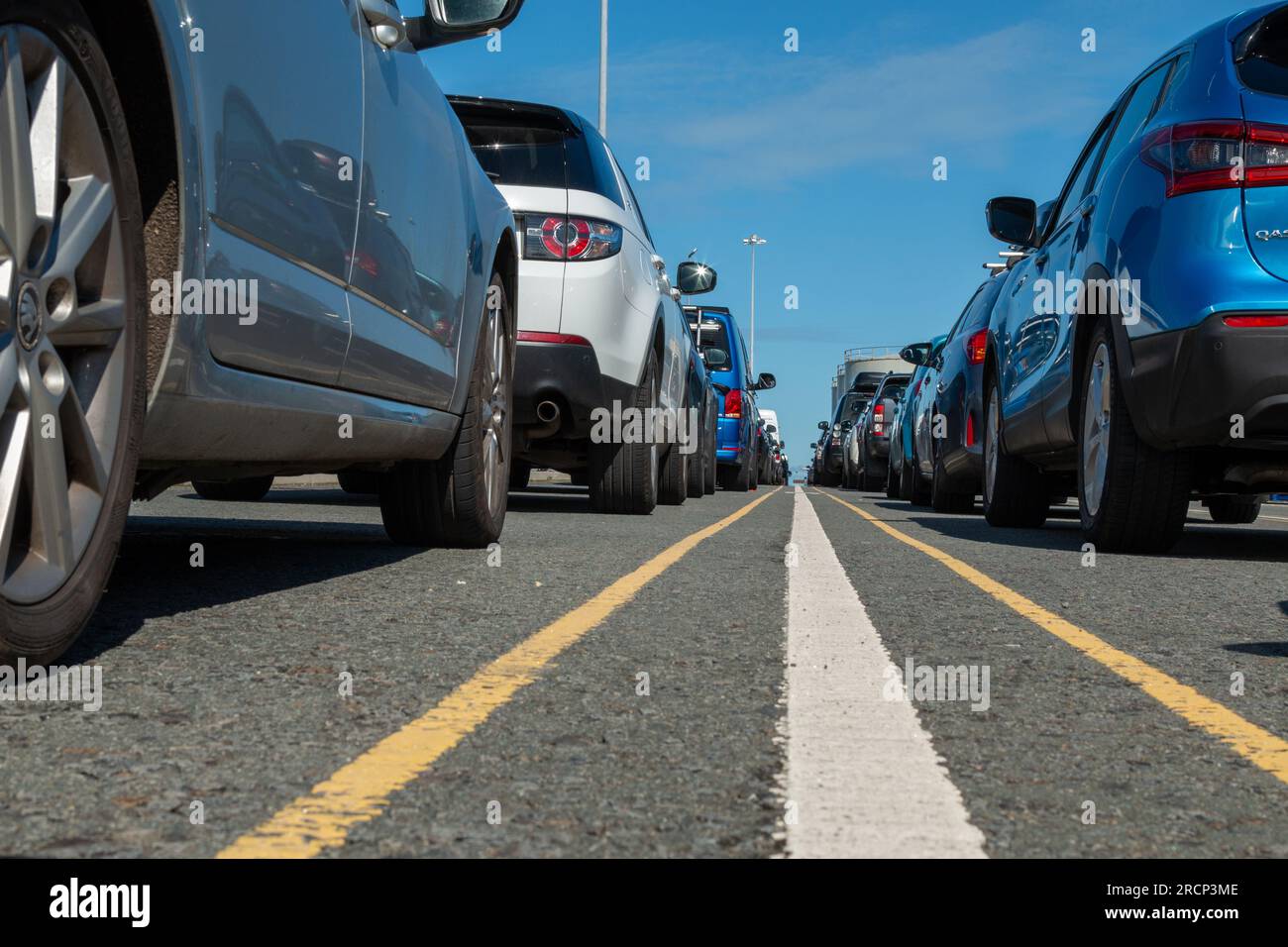 Two queues of cars waiting on either side of white and yellow lines ...
