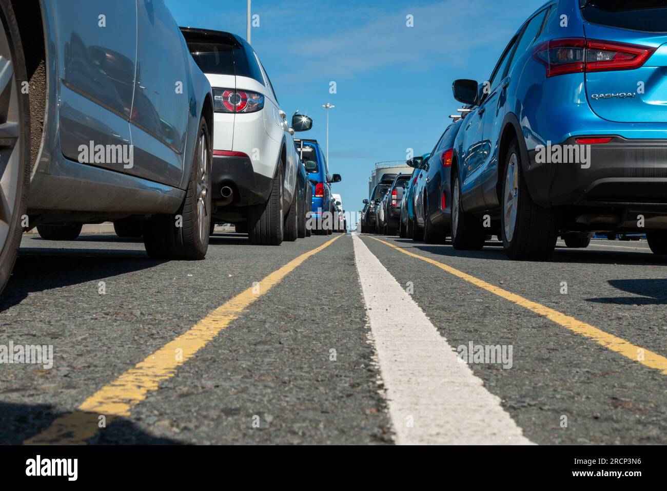 Two queues of cars waiting on either side of white and yellow lines ...