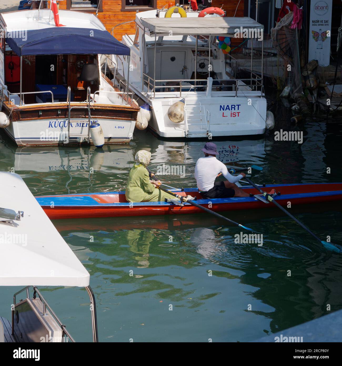 Male rowing instructor talks to female muslim student in a rowing boat ...