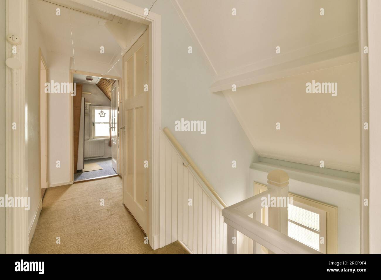 a long hallway with white trim on the walls, and carpeted stairs ...