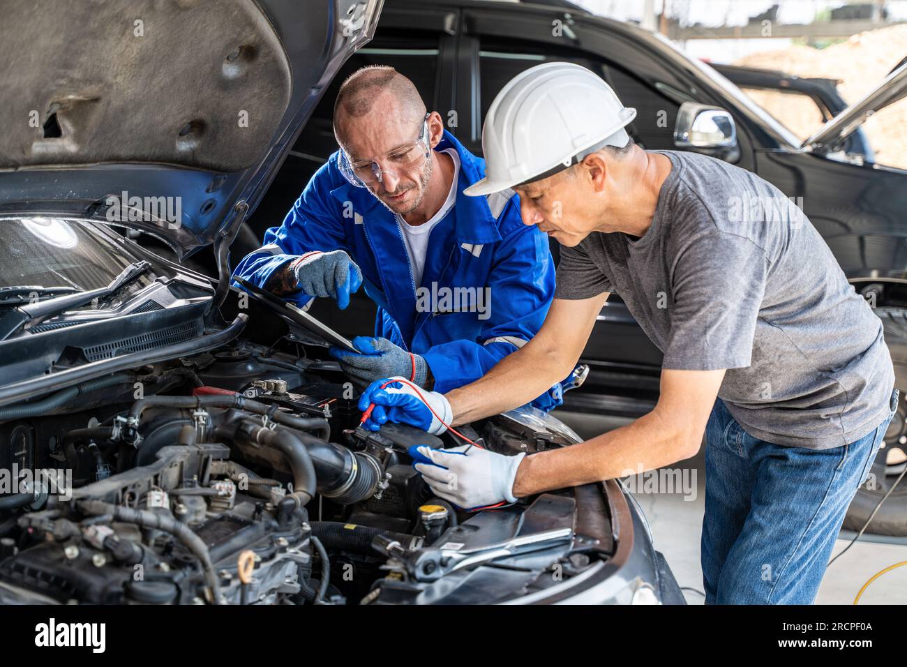 Two auto mechanics using a computer measuring device to check the car ...