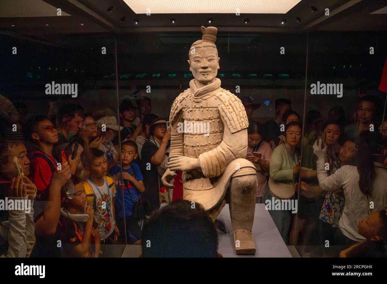 Visitors take photos of an excavated figure on display at the Museum of ...