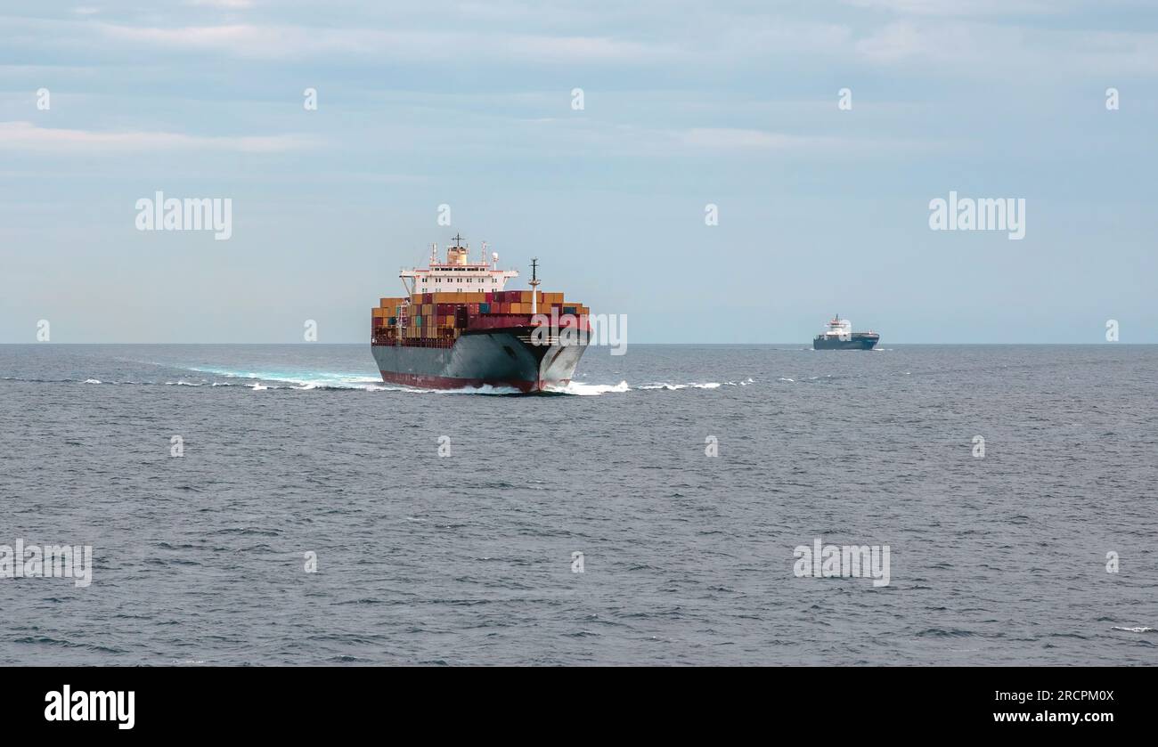 Container cargo ship full loaded in wavy sea reaches the port. Import ...