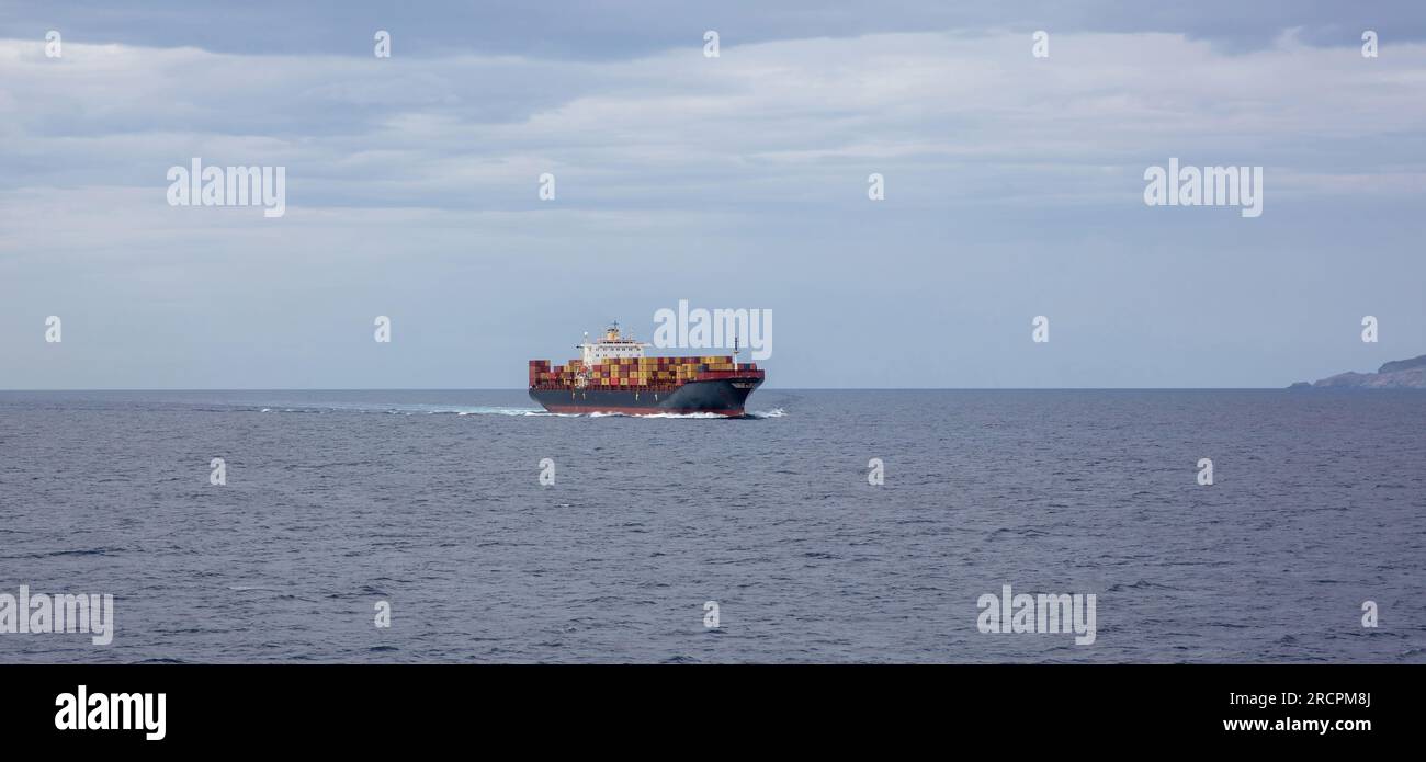 Container cargo ship full loaded is sailing in open wavy sea background ...