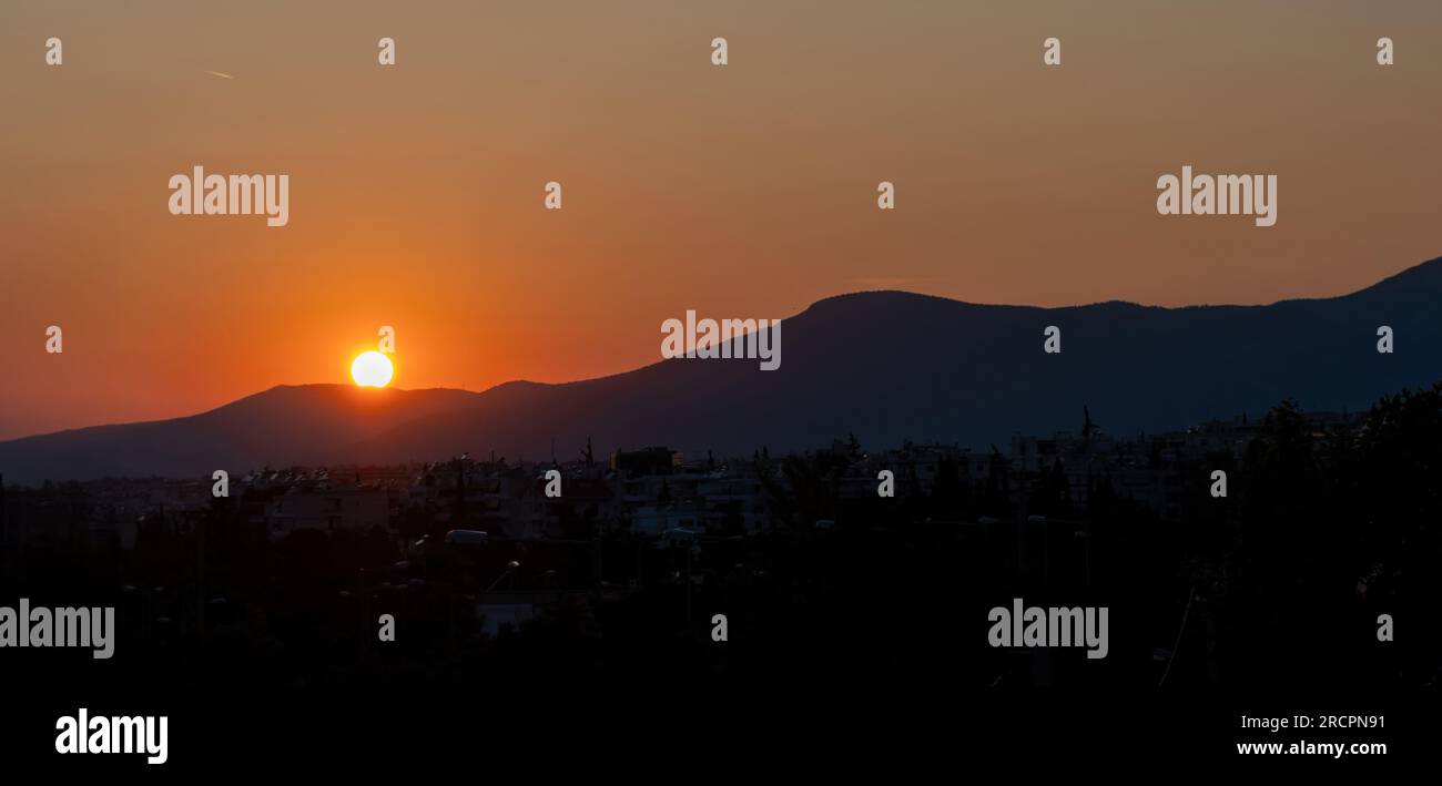 Sunset over city. Golden sun colors the sky with orange, red color and ...