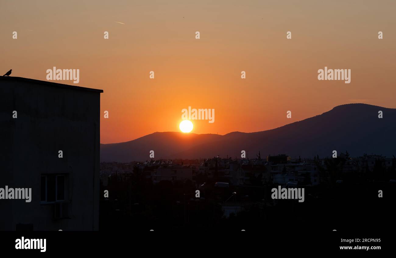 Sunset over city. Golden sun colors the sky with orange and red color ...