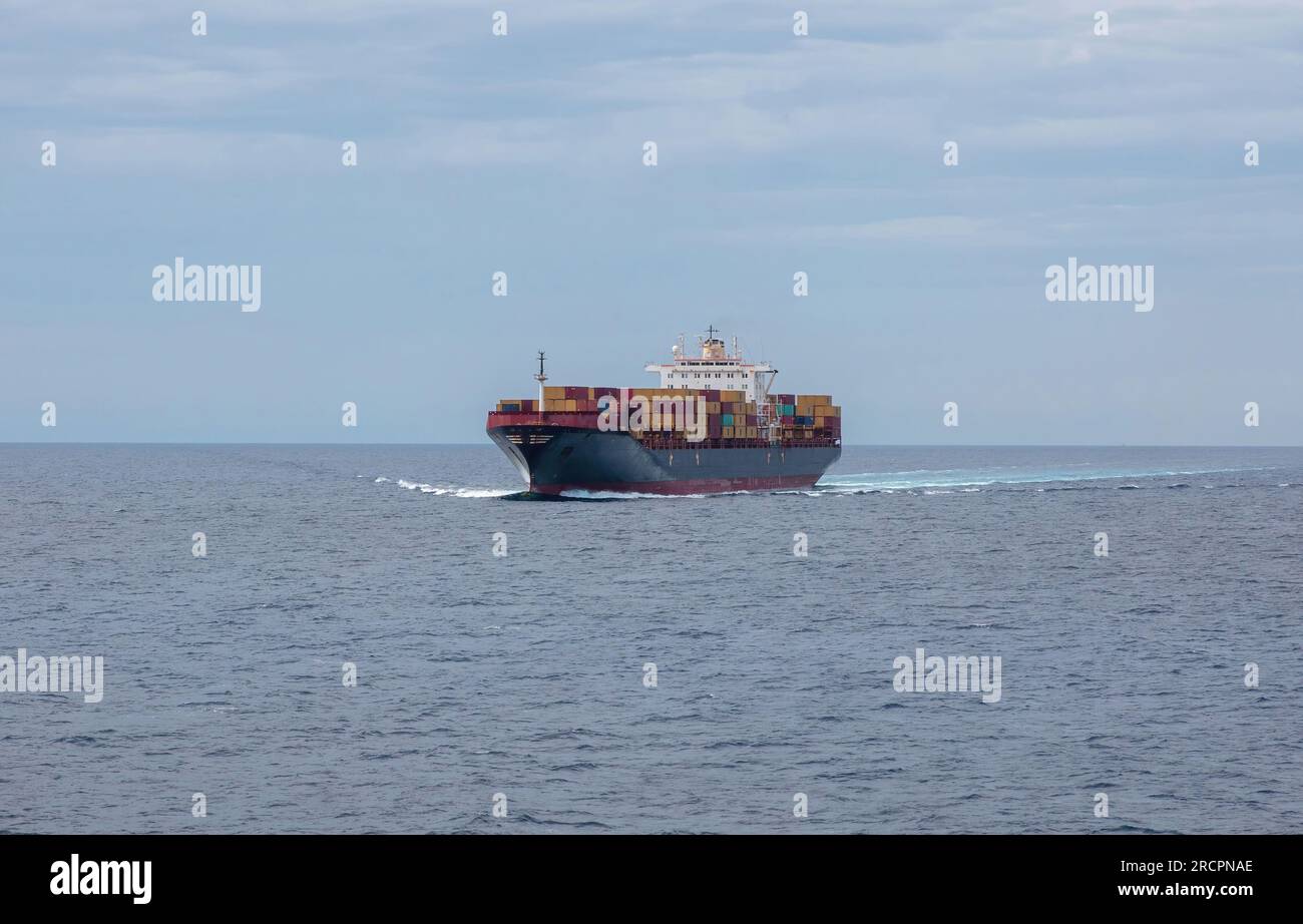Container cargo ship full loaded in wavy sea reaches the port. Import ...