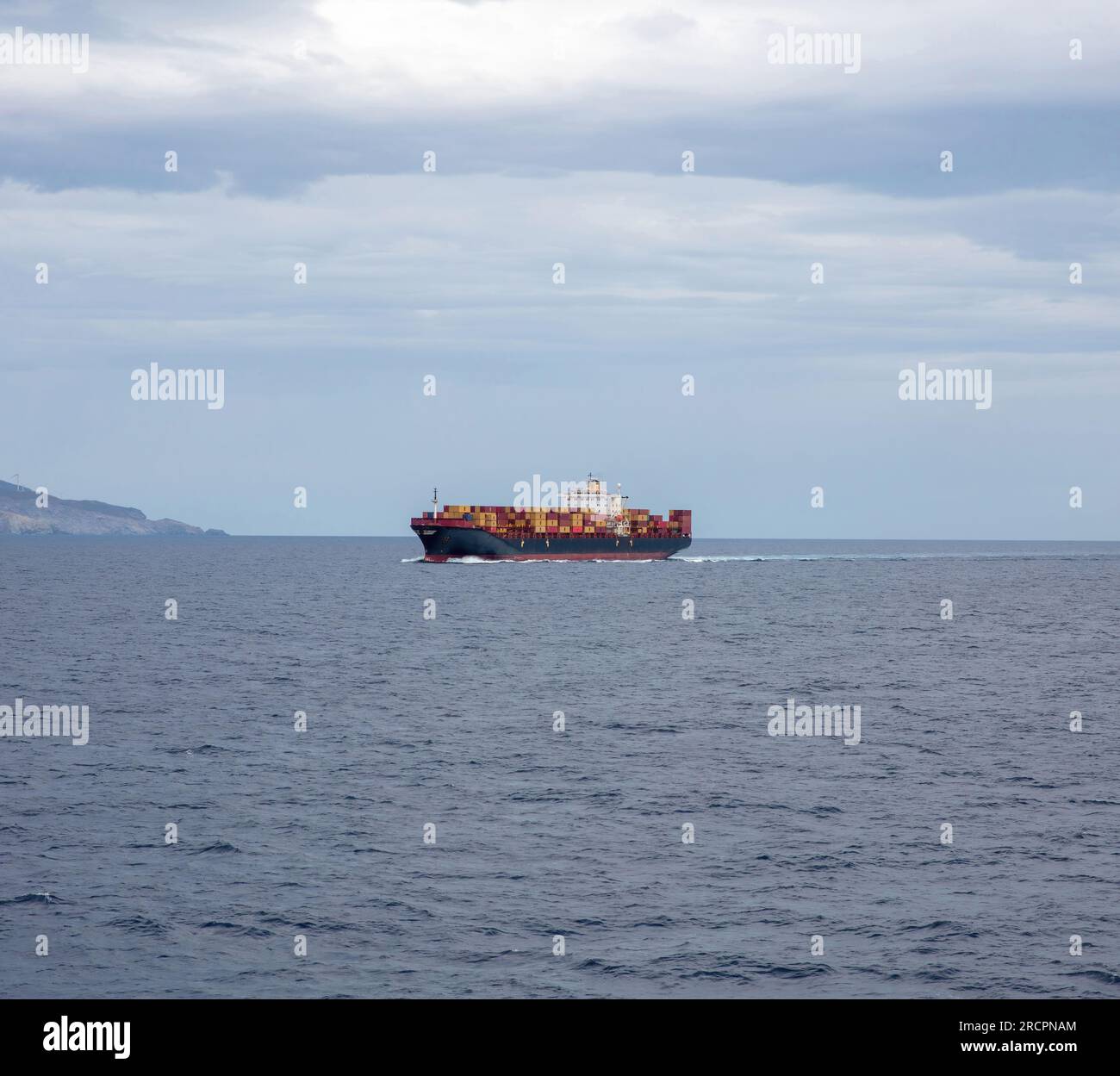 Container cargo ship full loaded is sailing in open wavy sea background ...
