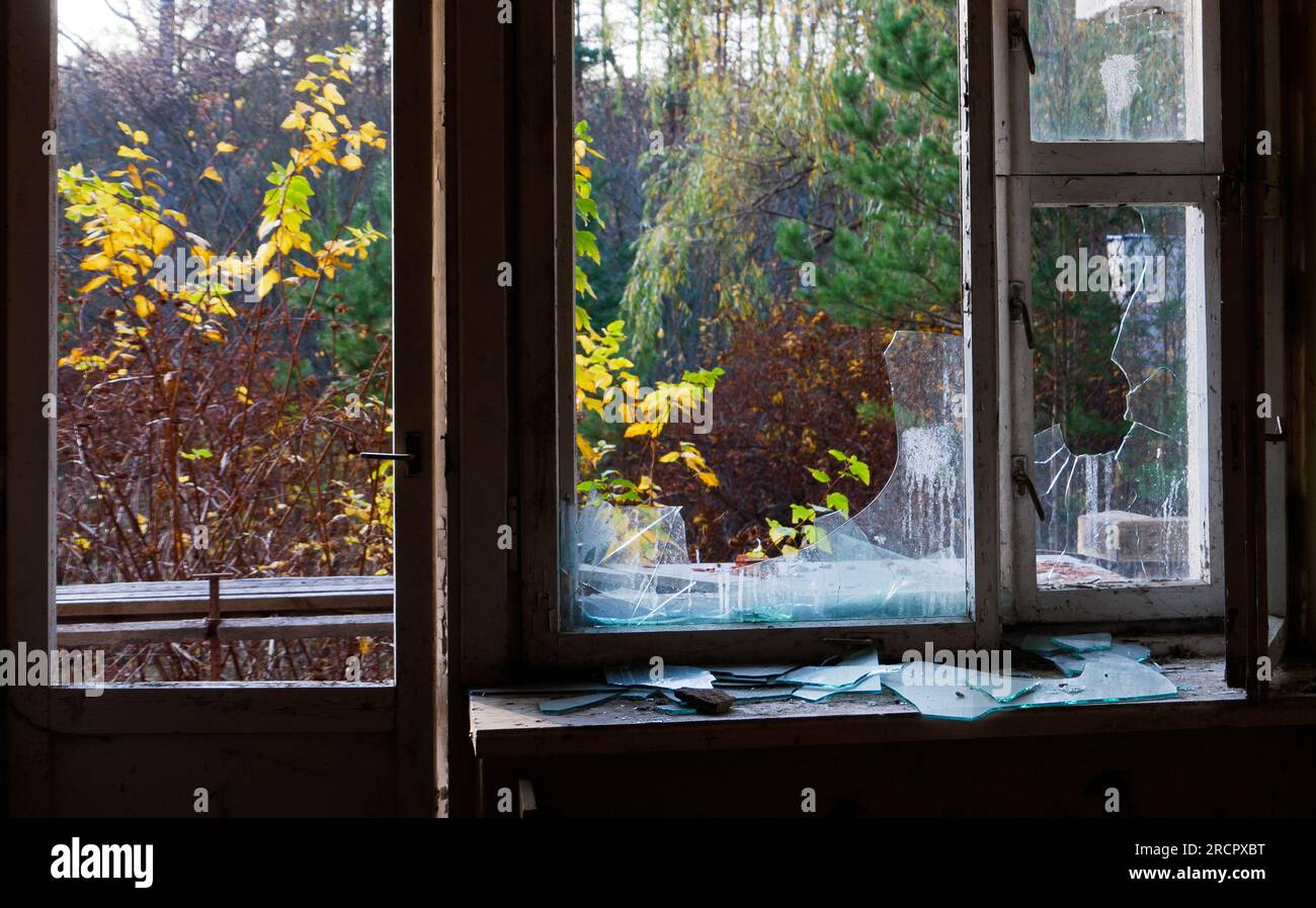 The big broken window in the abandoned building with autumn colorful ...