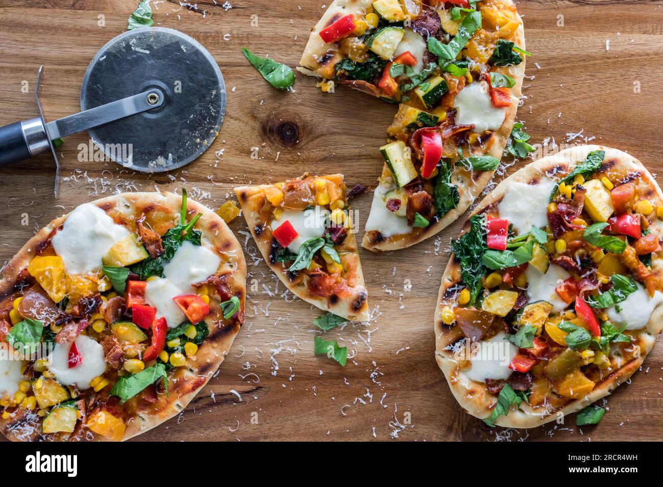 Top down view of whole and cut homemade summer garden pizzas with pizza ...