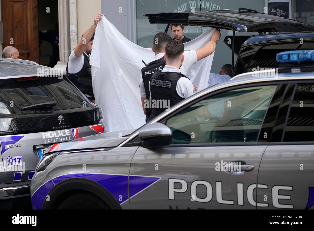 Police officers hide a corpse being loaded in a hearse outside Jane ...