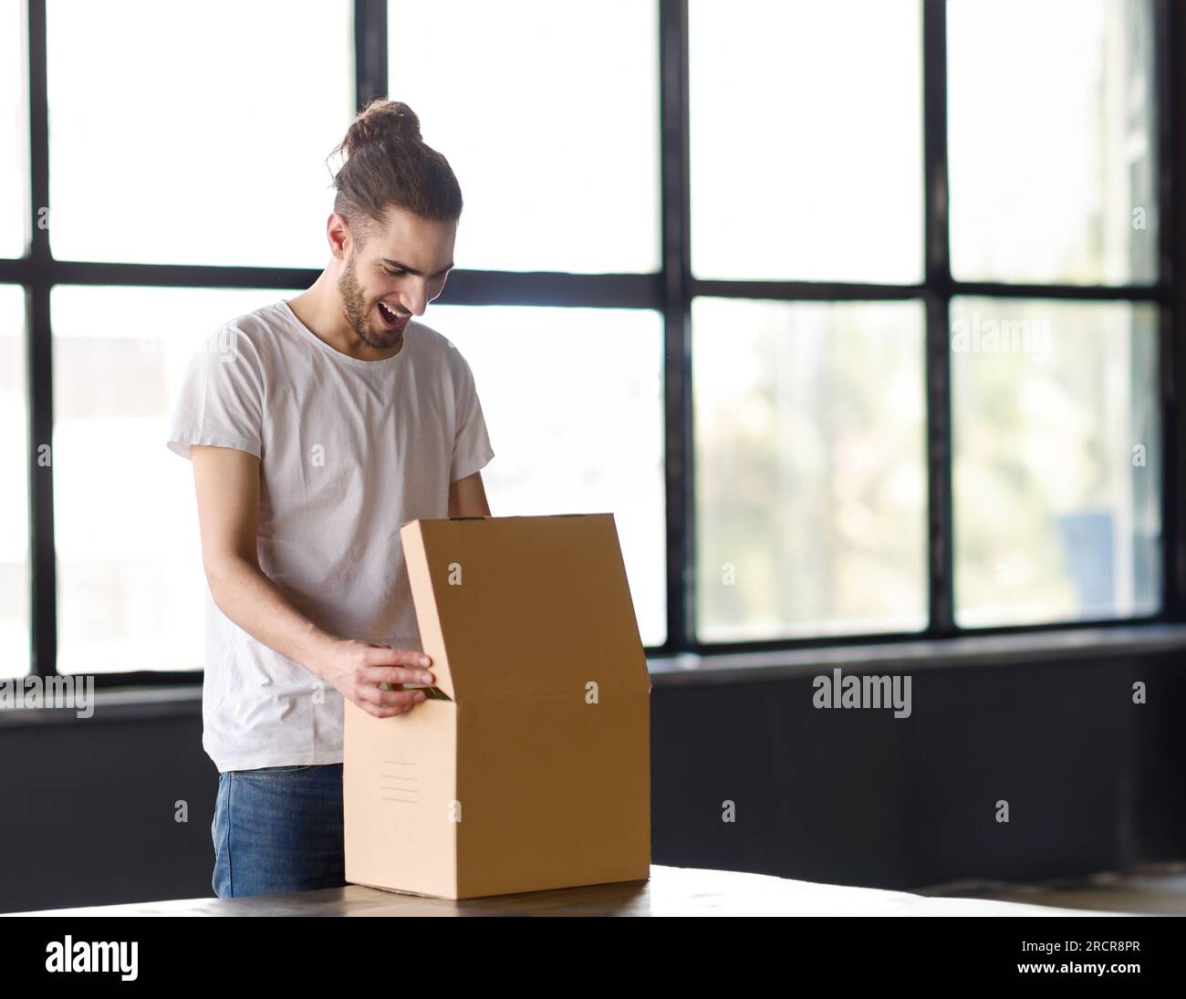 Excited Middle Eastern Young Man Opening Cardboard Box In Office Stock ...