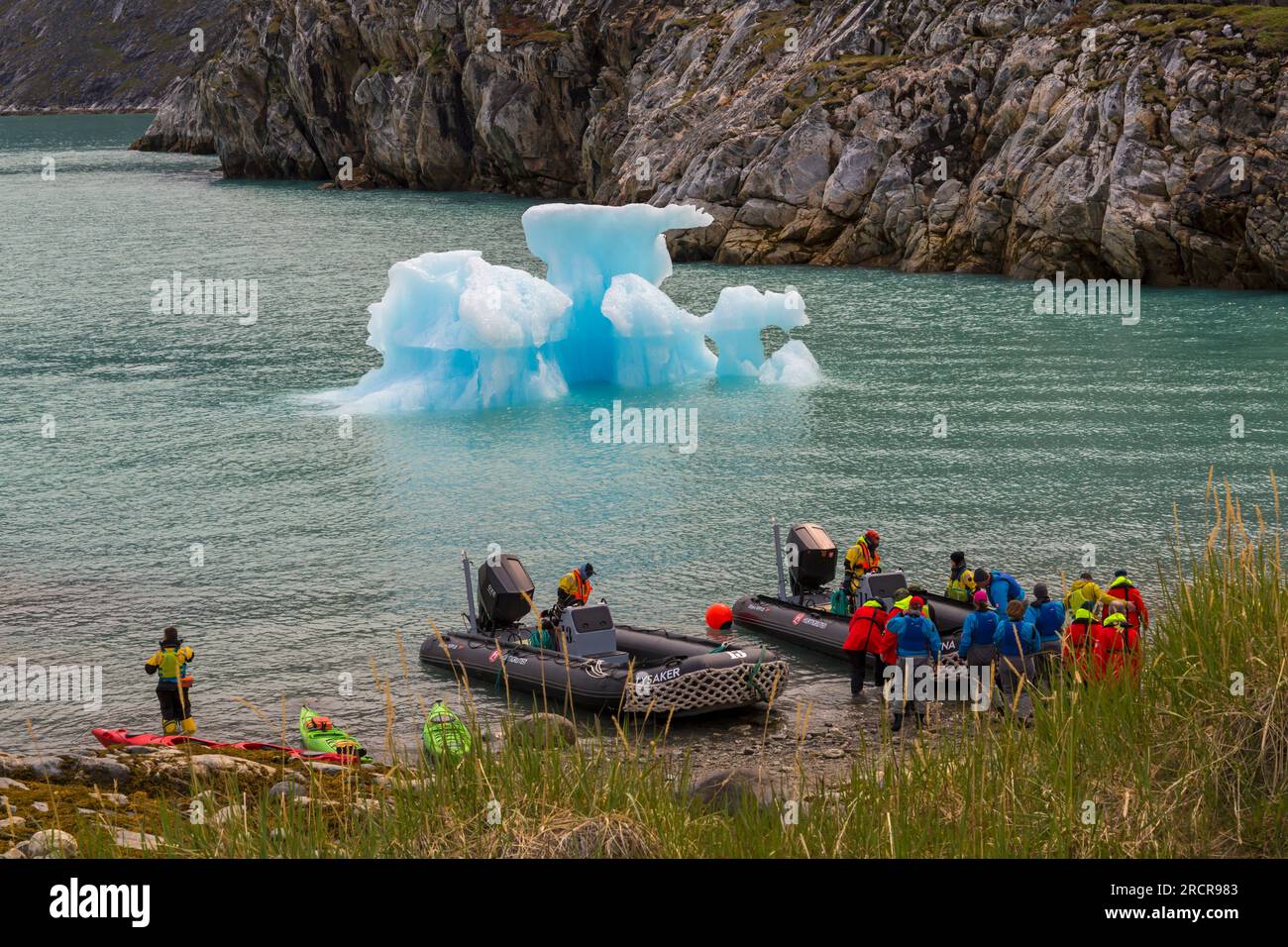 Tourists and expedition team with zodiacs and kayaks in bay with ...