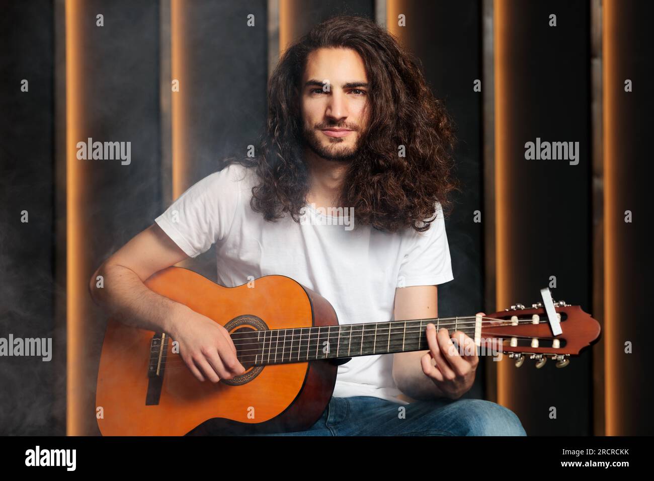 Musician Guy With Long Hair Holding Guitar In Dark Studio Stock Photo ...